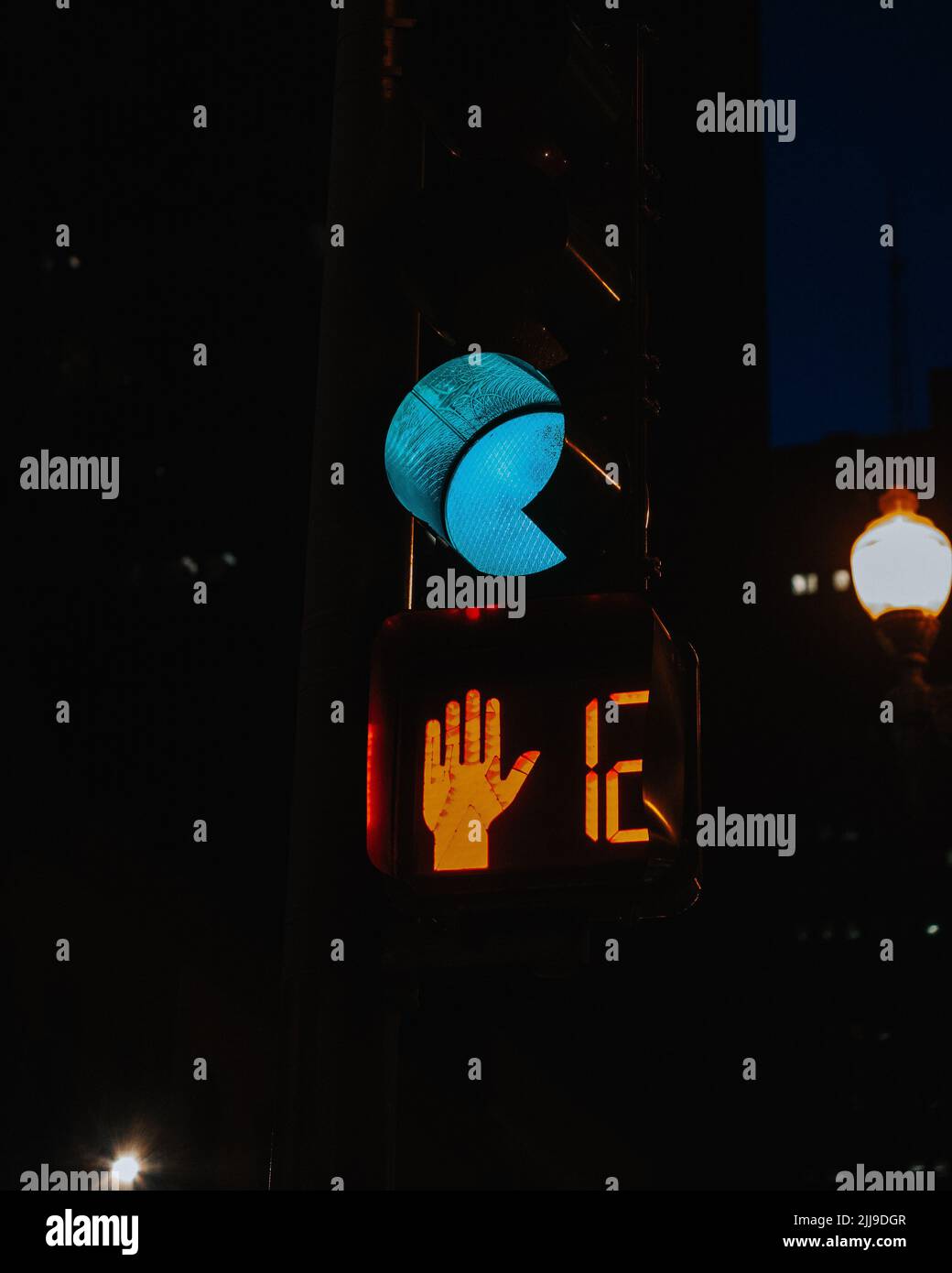 A vertical closeup shot of a traffic light with a hand giving a stop ...
