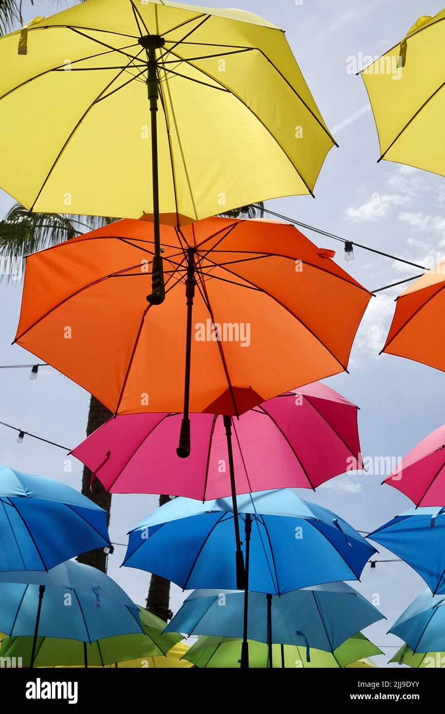A group of different colored umbrellas hang overhead a walkway Stock ...