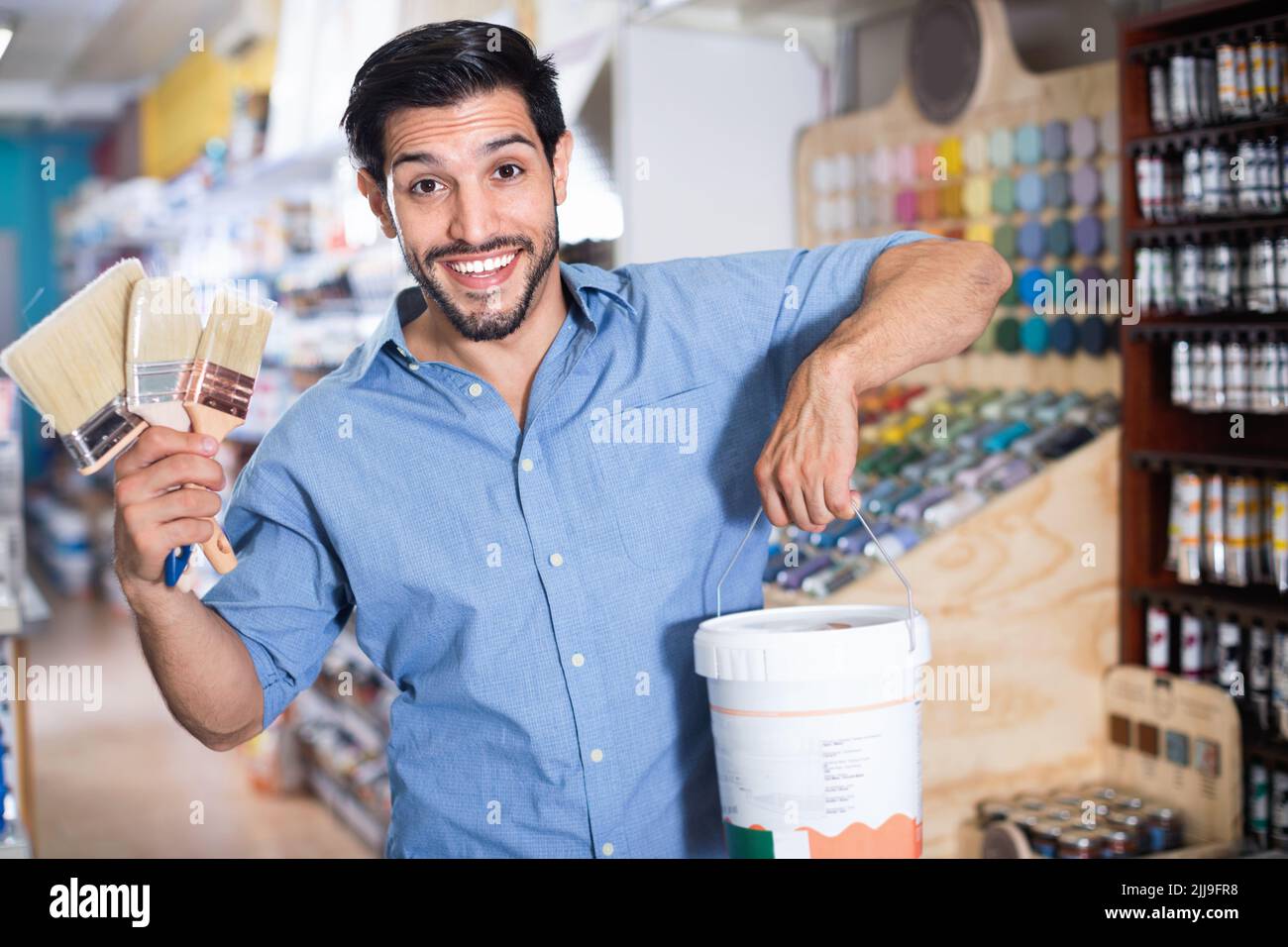 Man standing amongst racks in paint store with brushes and paint Stock ...