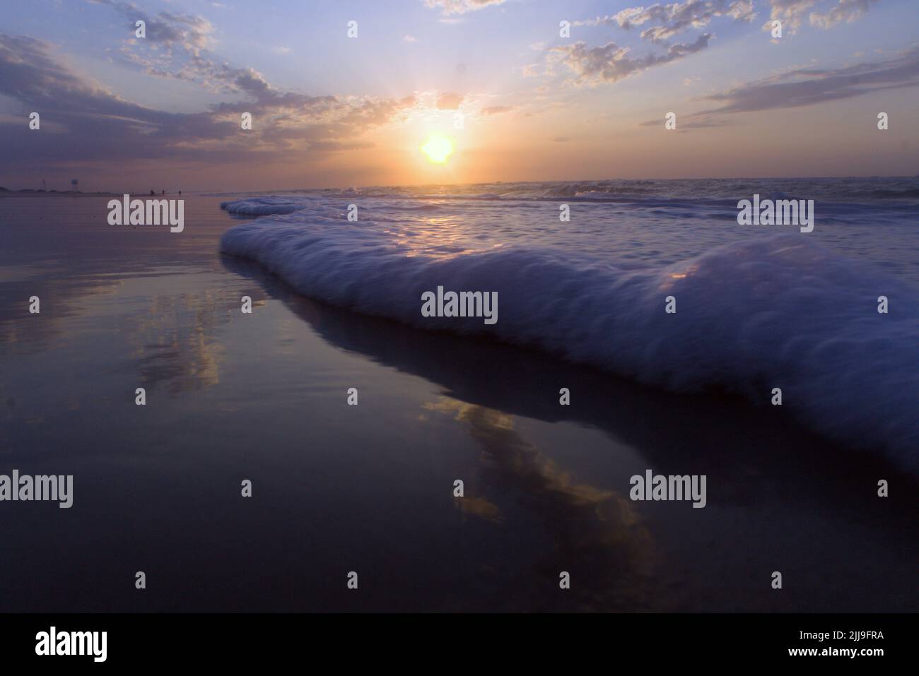 Beautiful sunrise with its reflection in the water on the beach with ...
