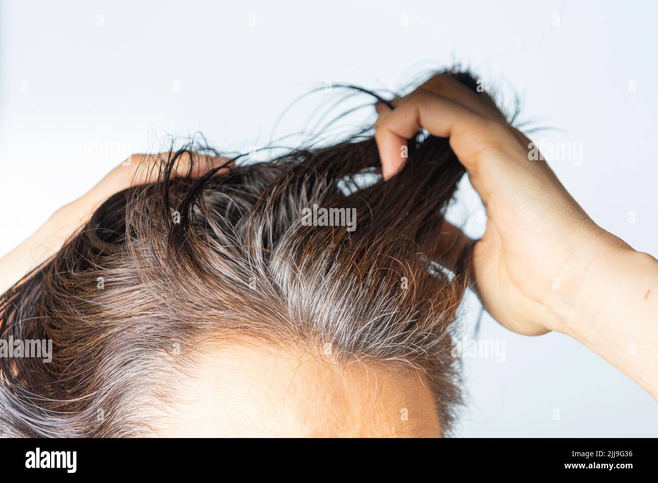 Head of middle age caucasian woman with black gray hair roots. Close up ...