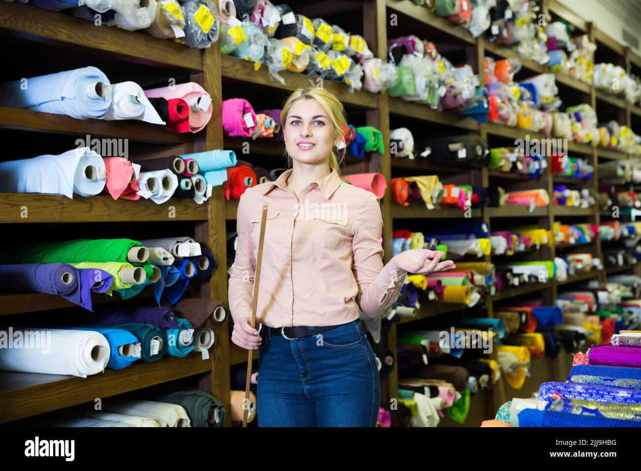 Female seller of fabric shop showing textiles Stock Photo - Alamy