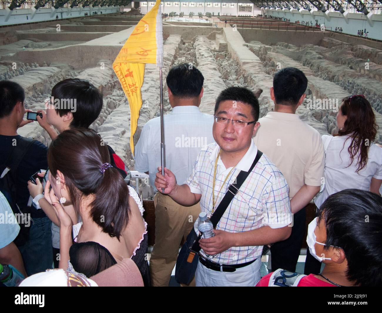 Tour guide with brightly coloured flag leading a party of Chinese ...