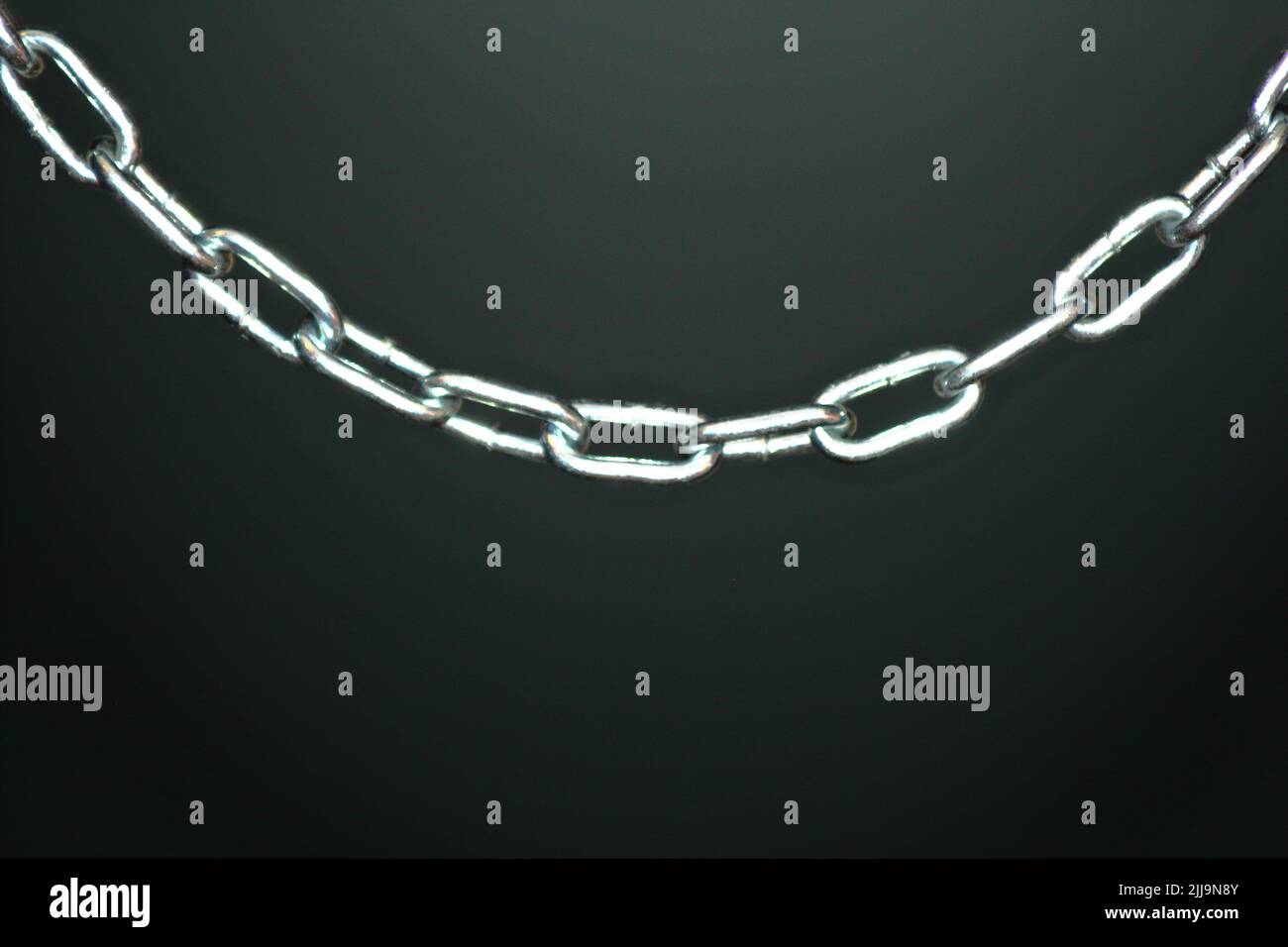 a stell metal chain is hanging and bulids the curve of a cosinus ...