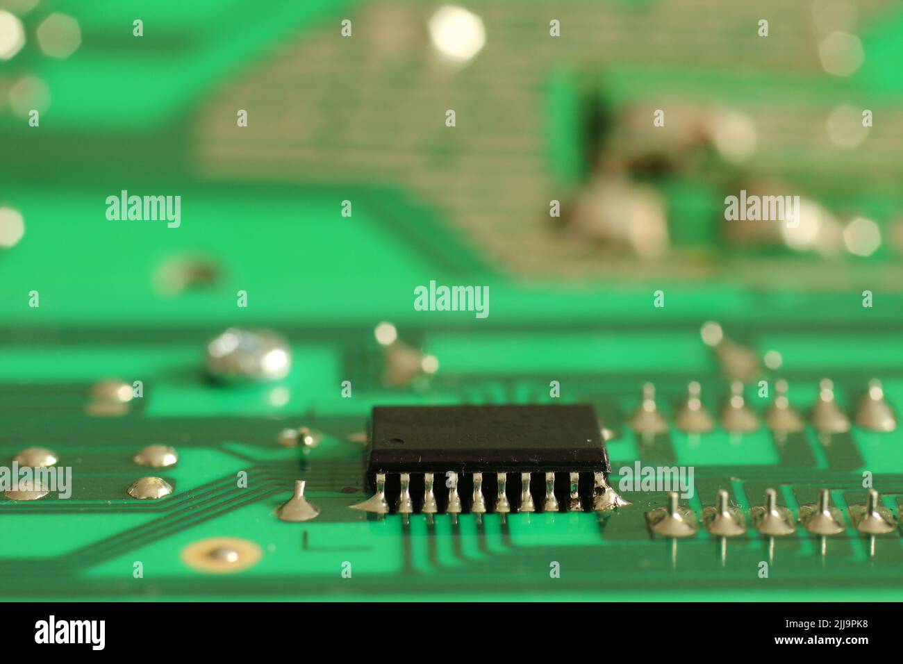 Close up of an electronic component on a green circuit board with deep ...