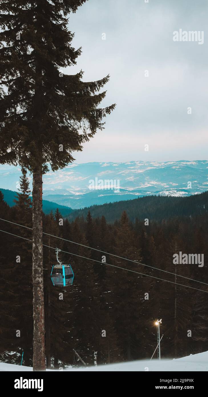 A winter ski resort with blue gondola cabin and snow mountains and ...