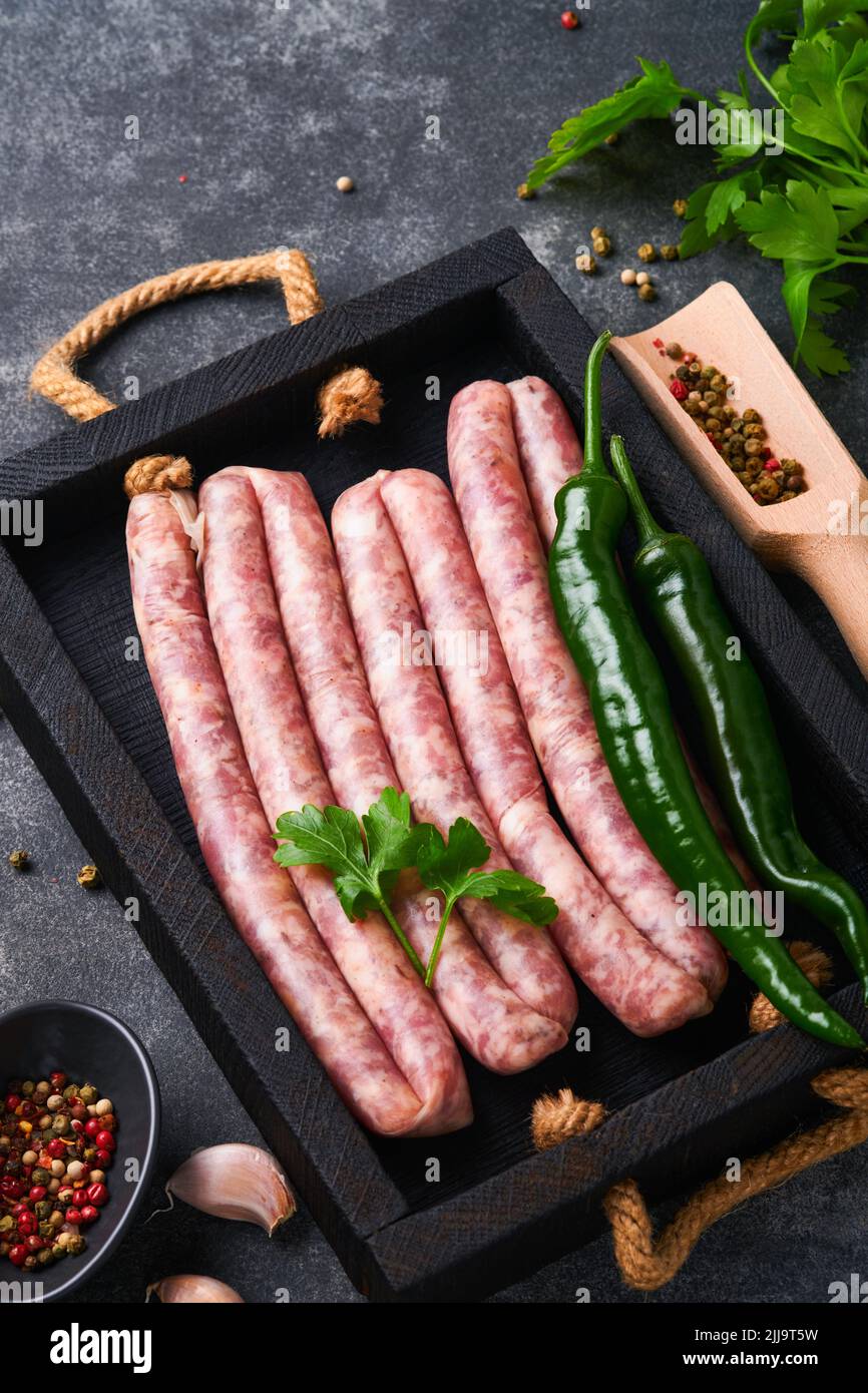 Raw sausages. Bratwurst or sausages with ingredients on cutting board ...