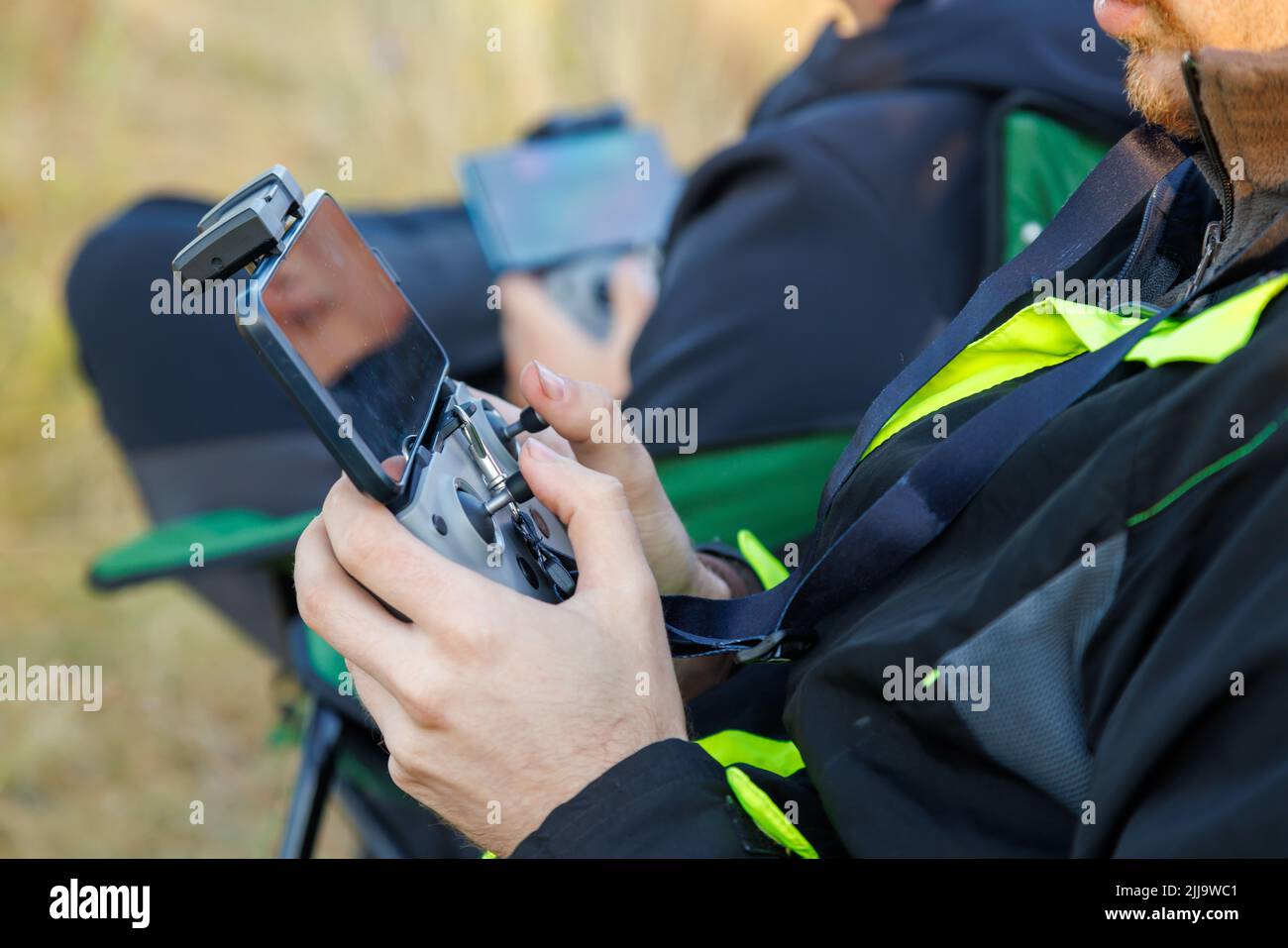 drone operator hands using remote control with sticks and cellphone as ...