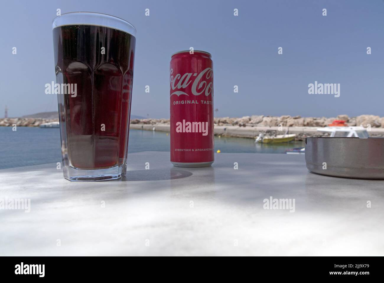 Greek language Coca Cola can and a glass of coke, at the harbour at ...