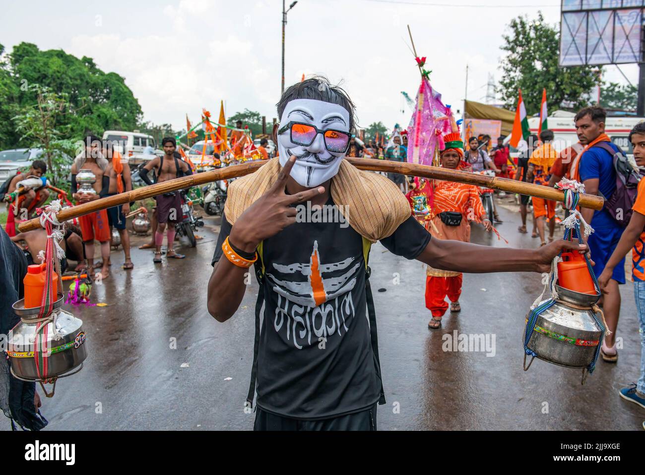 Kanwariya wearing a mask carries holy water during annual Kanwar Yatra ...