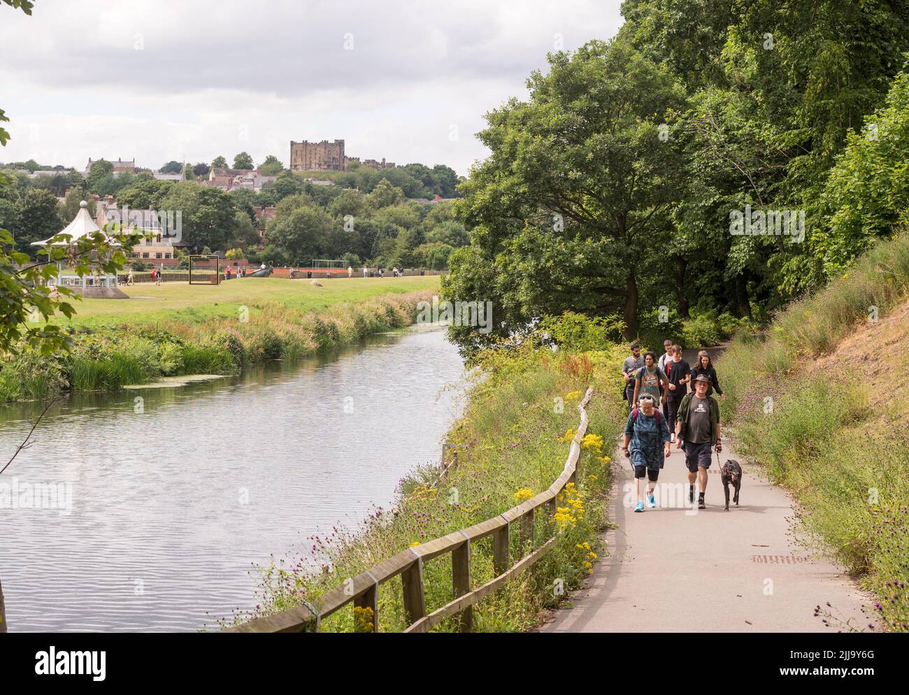 A group of people walking along Durham riverside path with the castle ...