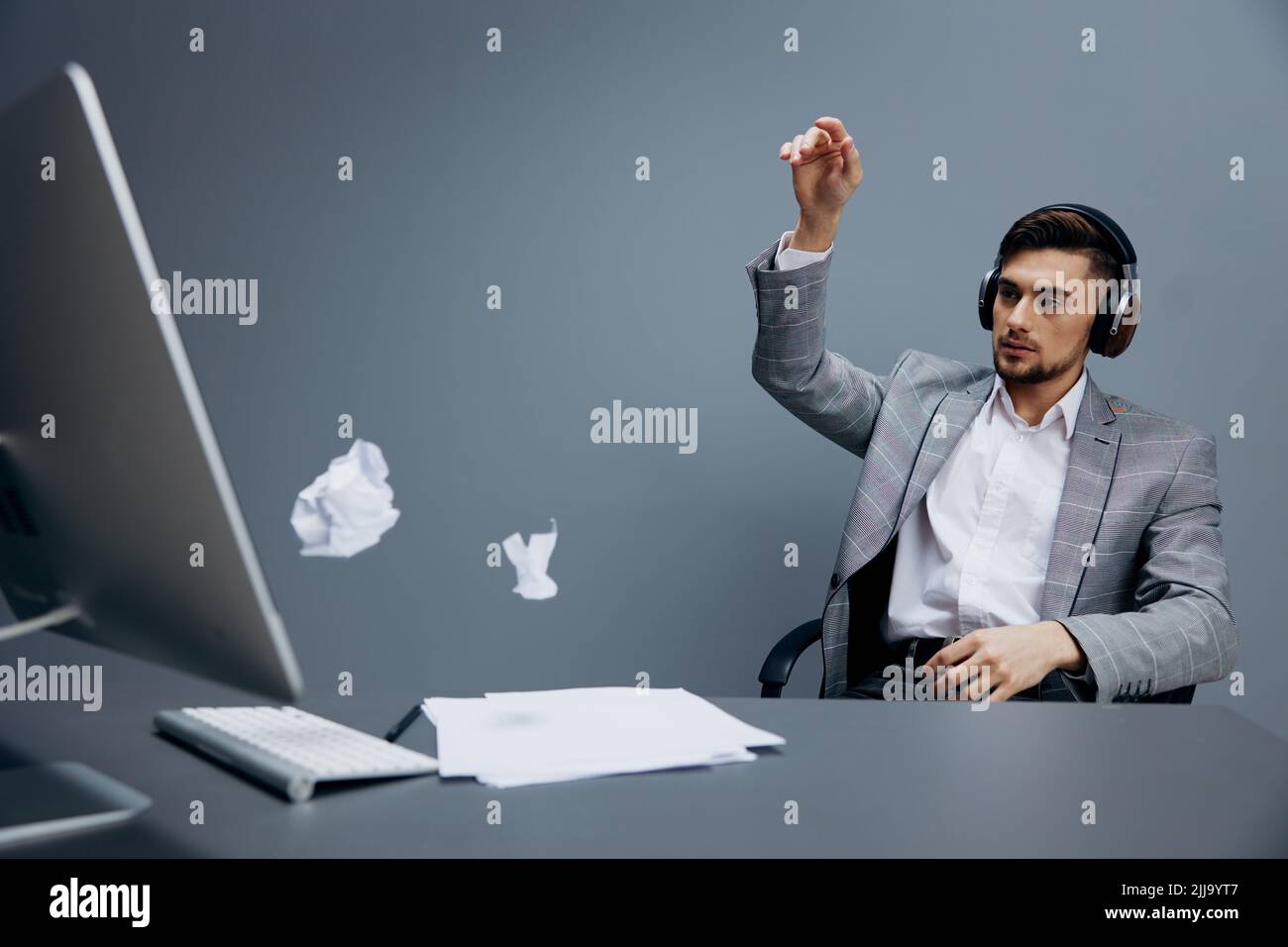 businessmen in headphones in a gray suit sits in front of a computer ...