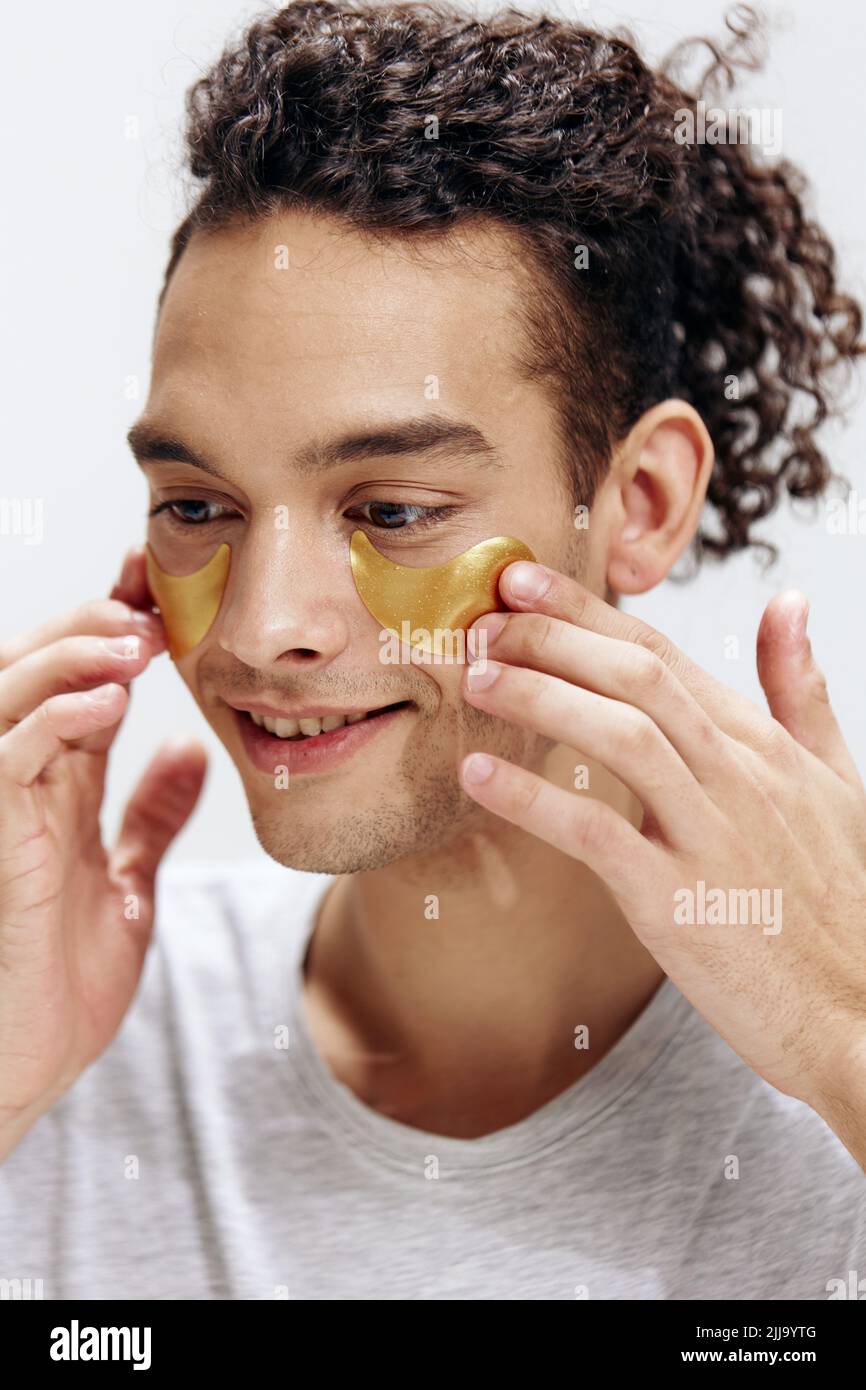 A young man golden patches on the face health cosmetology isolated ...