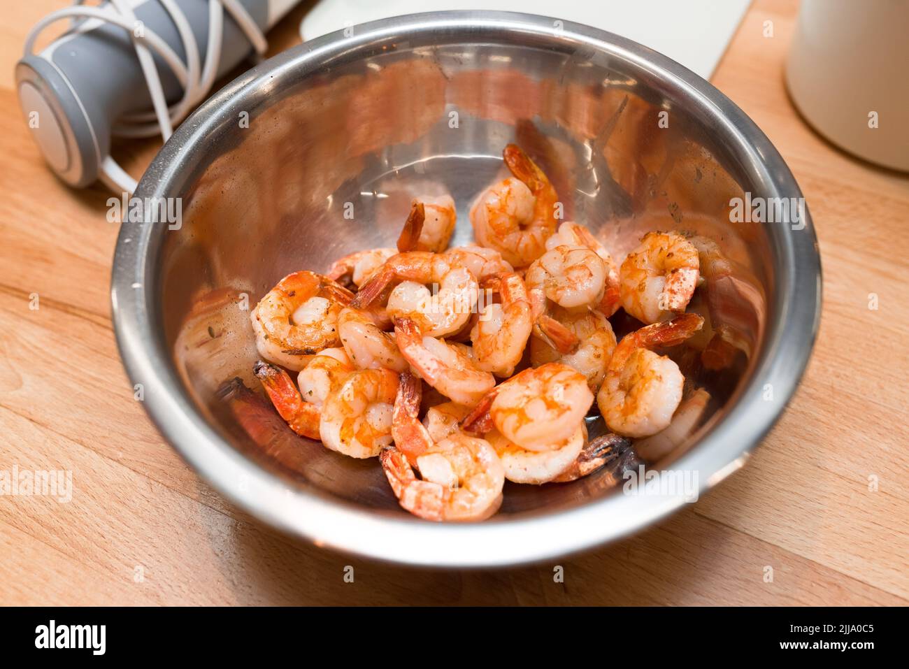 A metal bowl of fried shrimp in spices with unpeeled tails, lots of ...