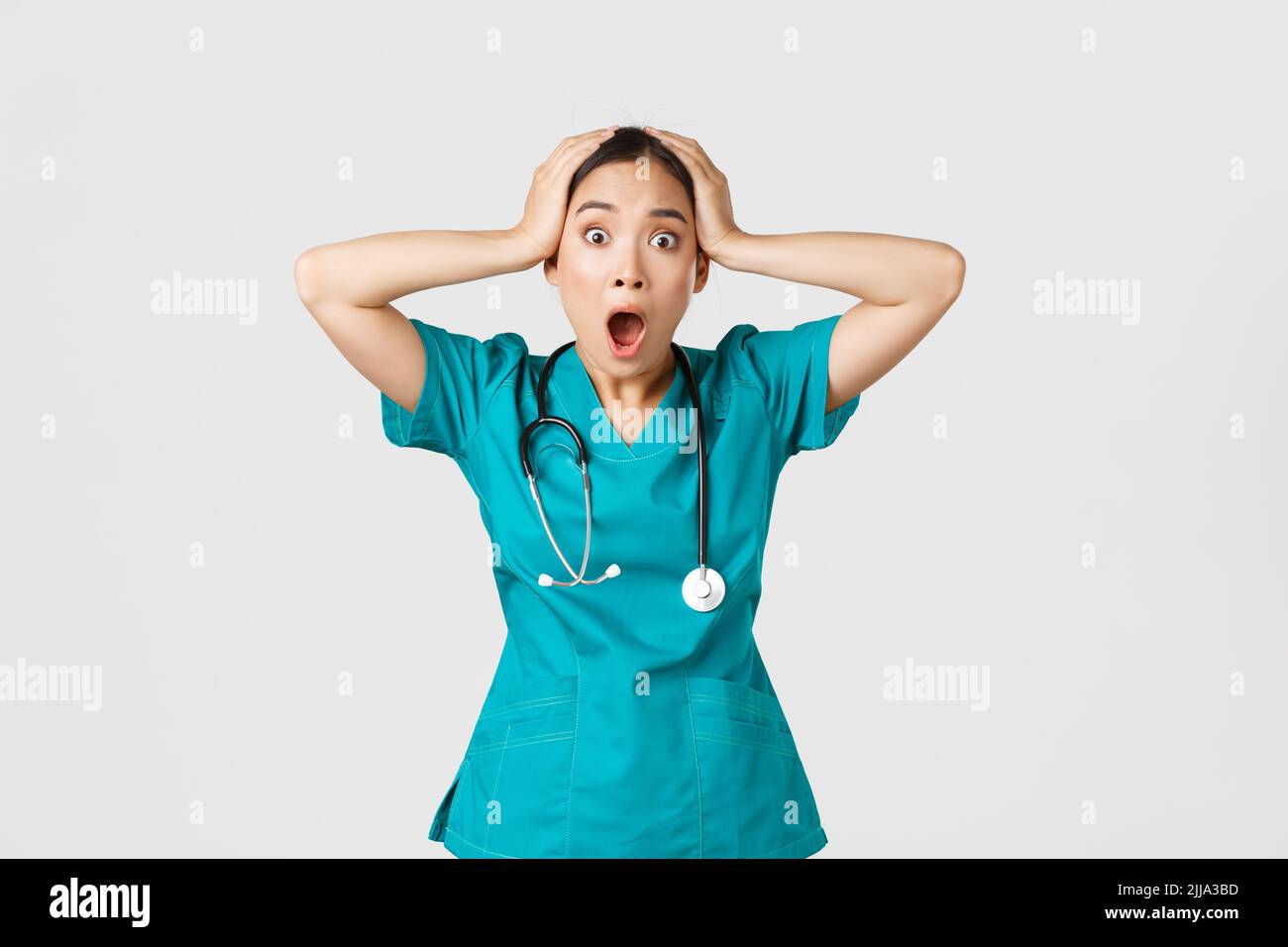 Covid-19, healthcare workers and preventing virus concept. Shocked and anxious asian female ...