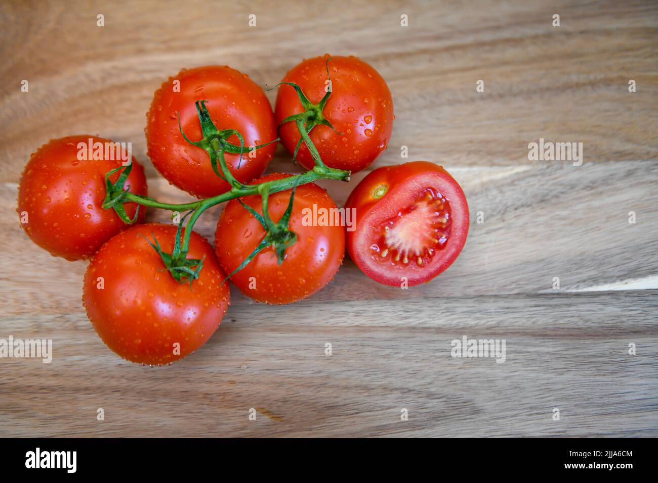 Red tomatoes on vine in kitchen - sliced and whole fresh tomato on wood ...
