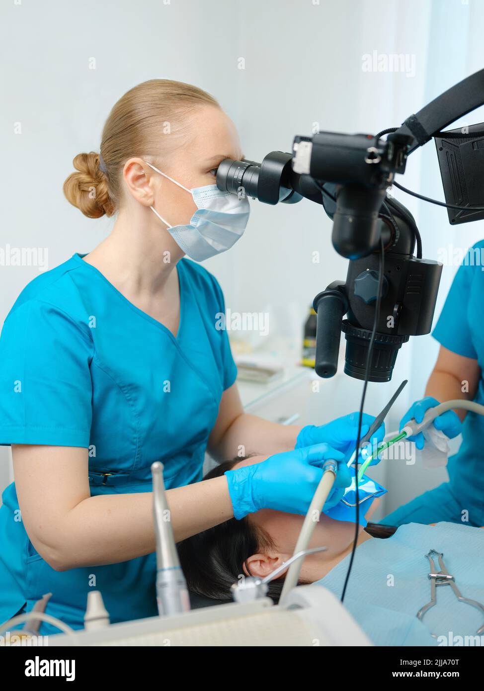Female dentist using dental microscope treating patient teeth at dental ...