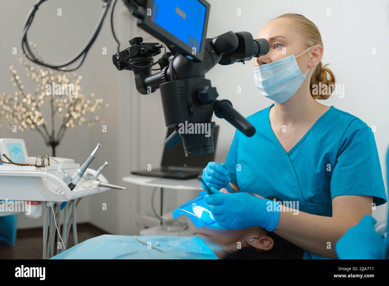 Female dentist using dental microscope treating patient teeth at dental ...