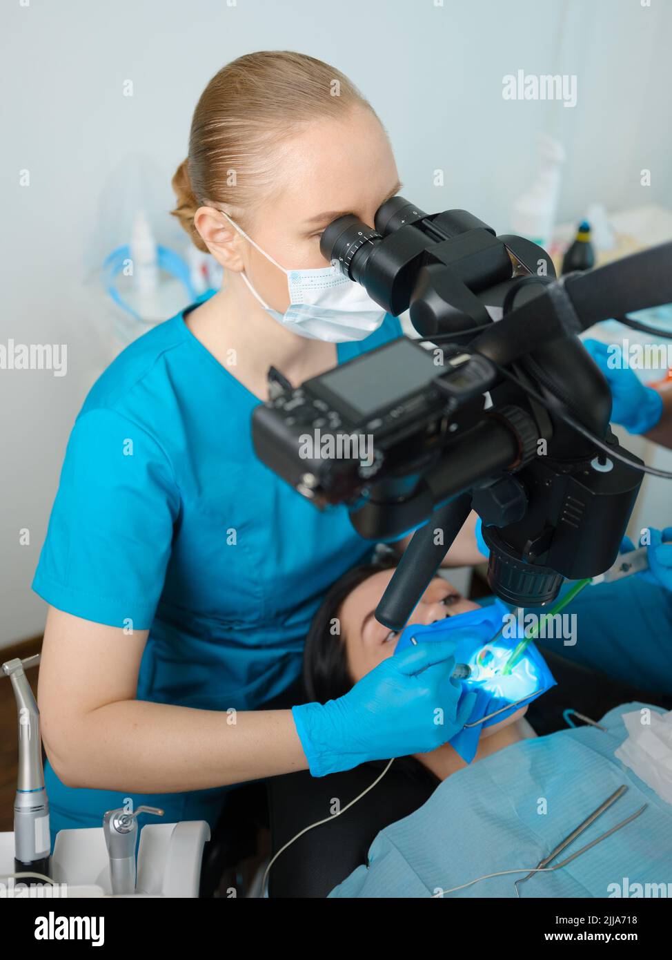 Female dentist using dental microscope treating patient teeth at dental ...