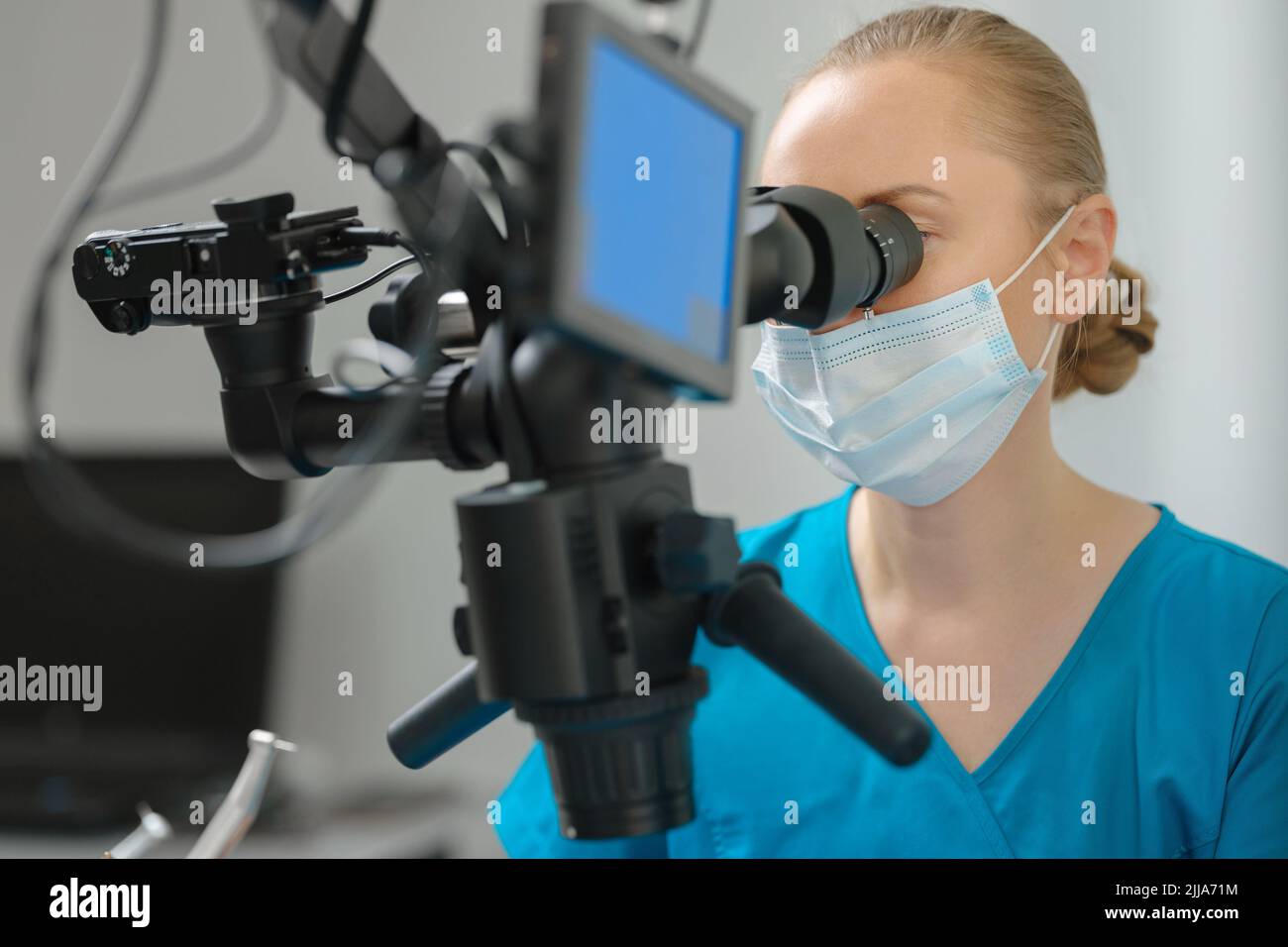 Female dentist using dental microscope treating patient teeth at dental ...