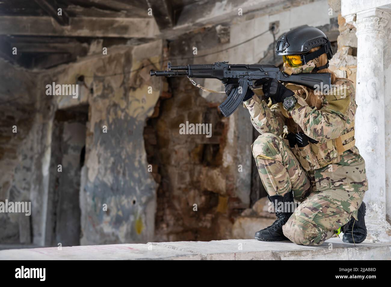 Portrait of a woman in a helmet and goggles with a machine gun in her ...