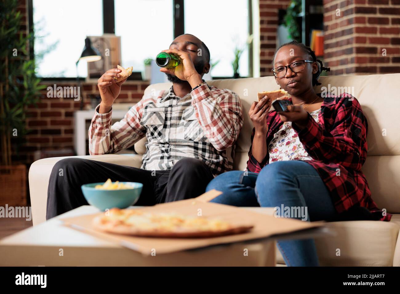 Boyfriend drinking beer from bottle and girlfriend eating pizza while ...