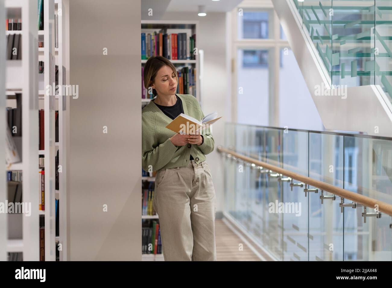 Focused pensive mature woman bookworm reading book in library. Lifelong ...