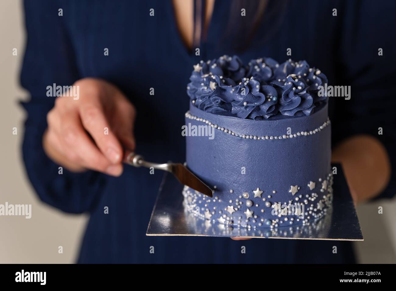 Birthday cake held by a baker in a bakery. The baker is out of focus ...