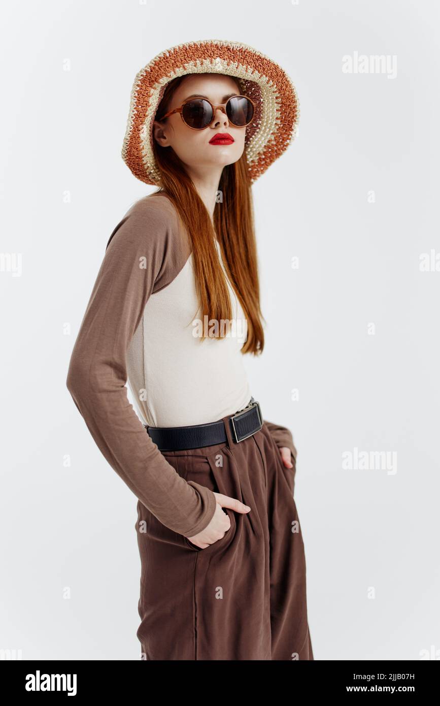 A serious fashion model in a hat and glasses poses with her hands in ...