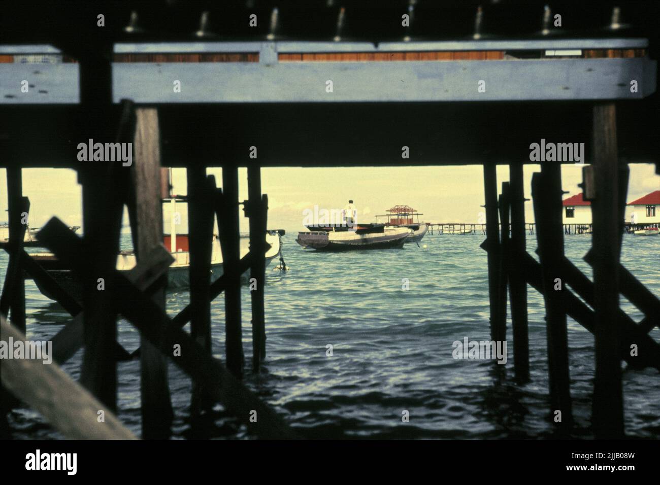 Wooden boats and tourism jetty are seen through a stilt building above ...