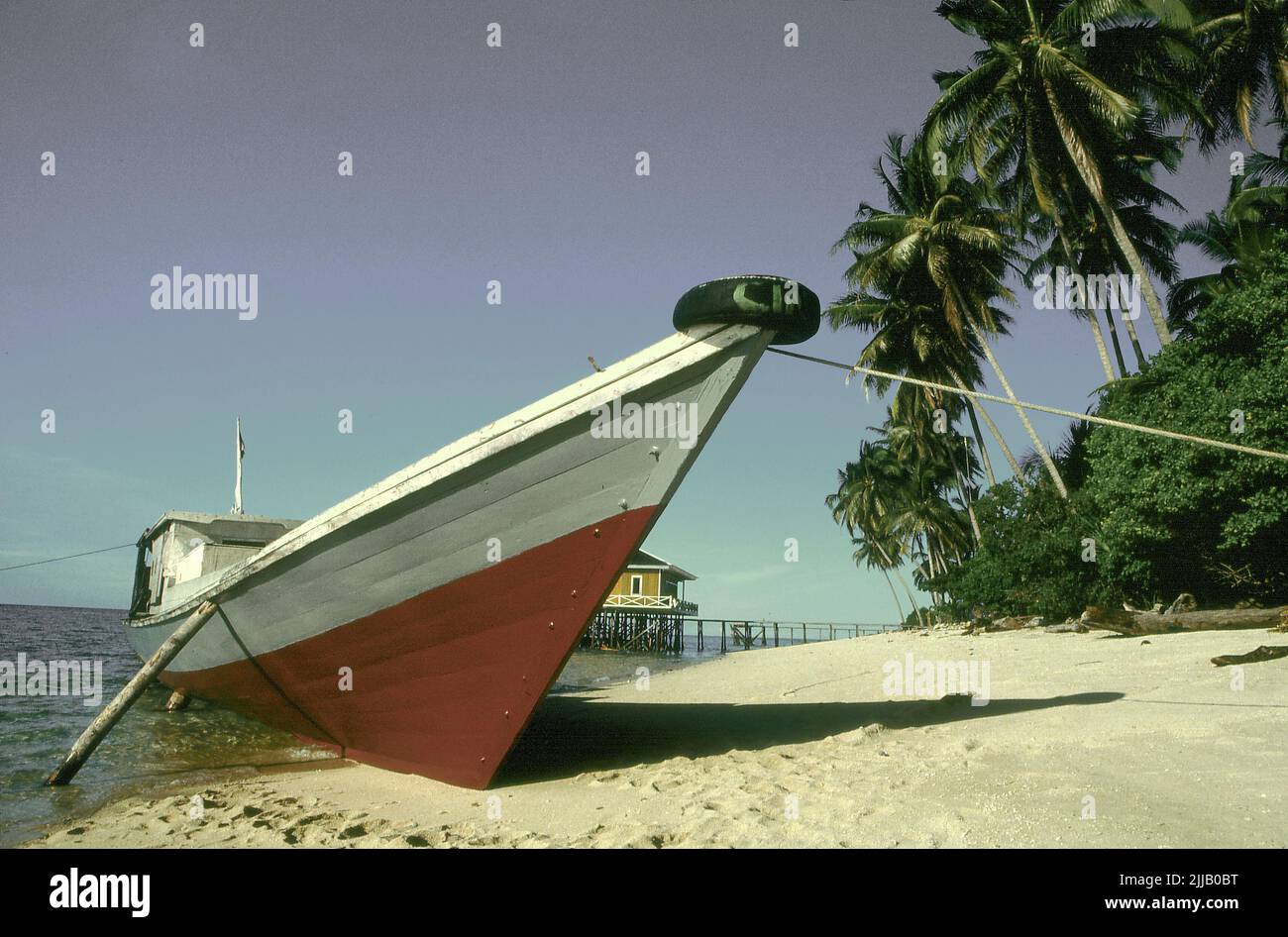 A boat in a background of a beach cottage in Derawan Island, a part of ...
