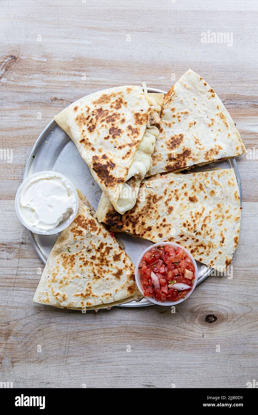 Chicken quesadilla cut in four pieces and served on a silver plate on a ...