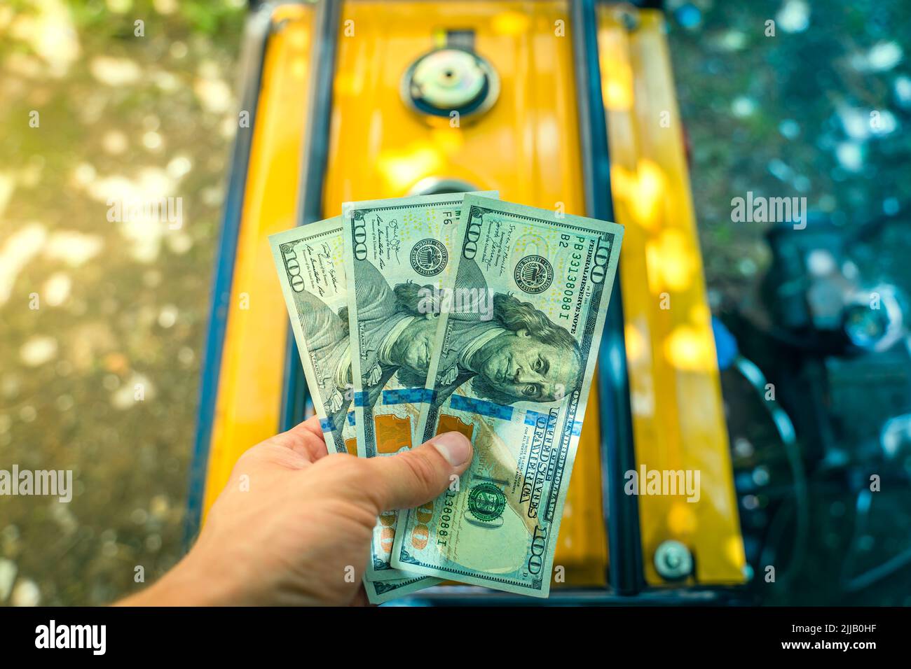 Buying a gasoline generator for dollars. A hand holds three one hundred ...
