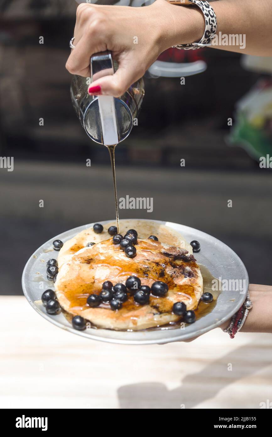 Woman's hand putting maple syrup on blueberry pancakes Stock Photo - Alamy