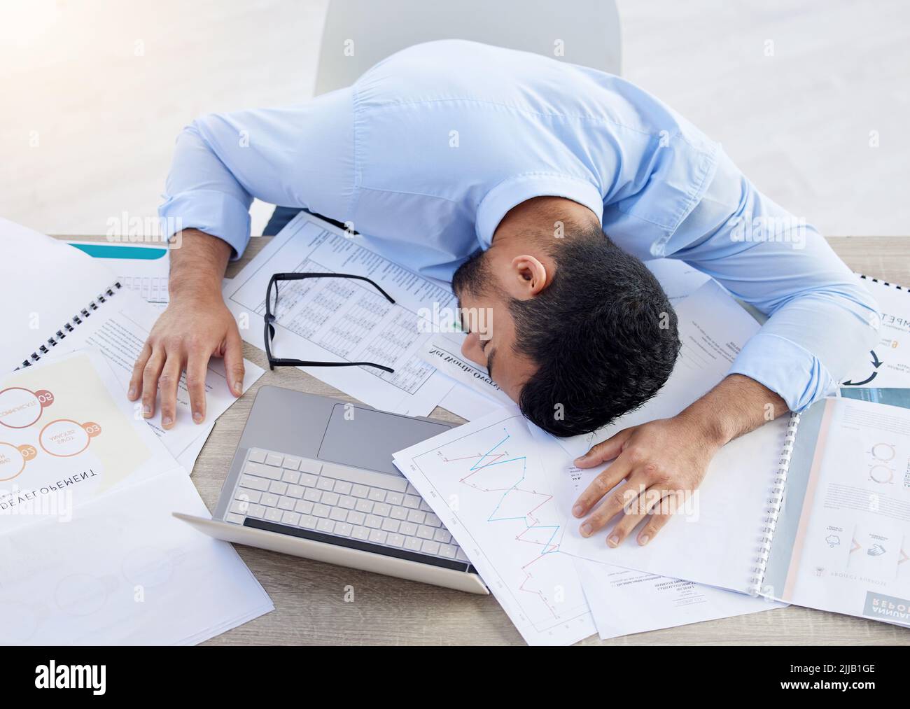 A little shut eye helps. a businessman taking a nap due to being ...