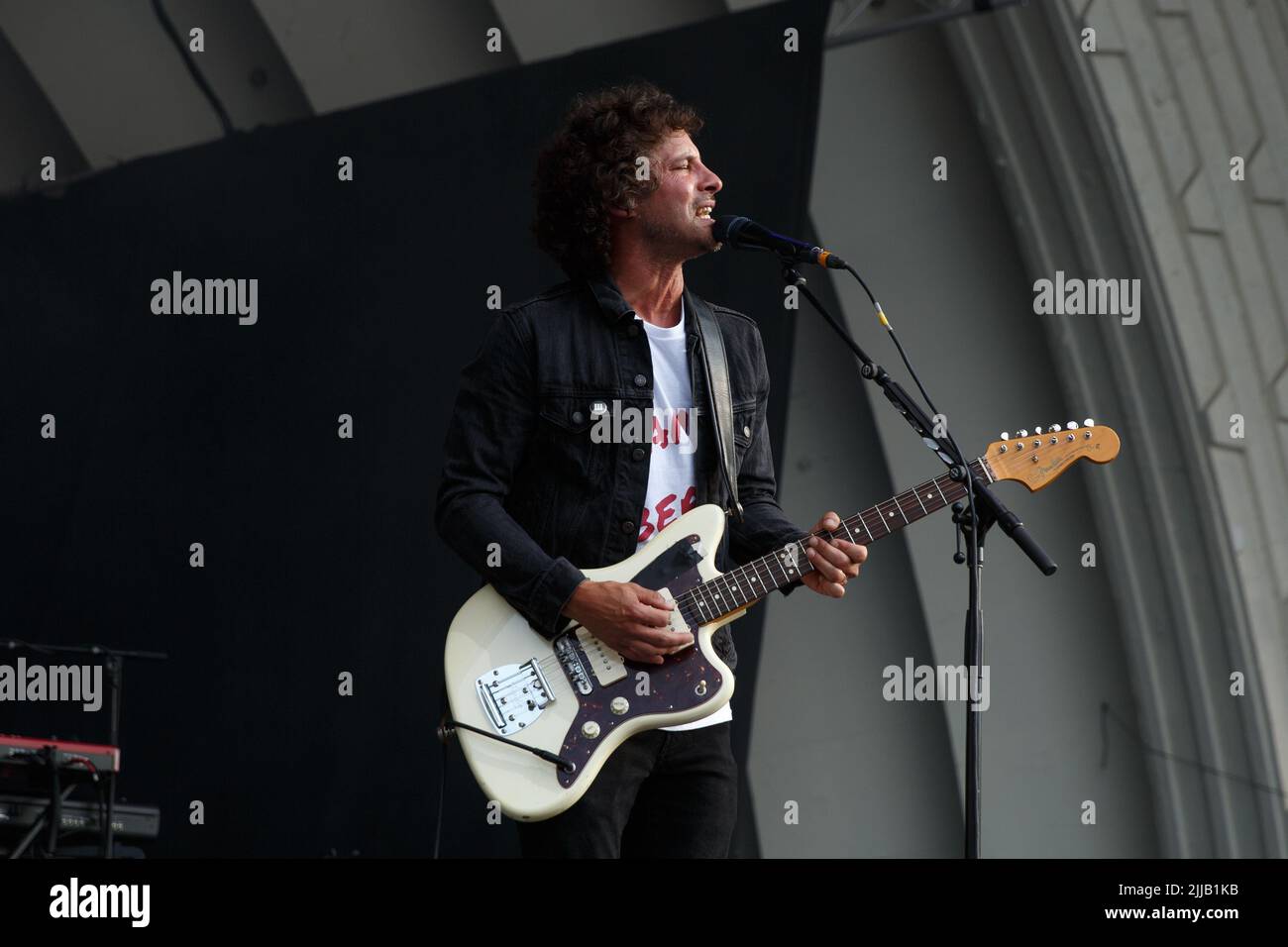 Sam Roberts plays guitar and sings on stage wearing a denim jacket and ...