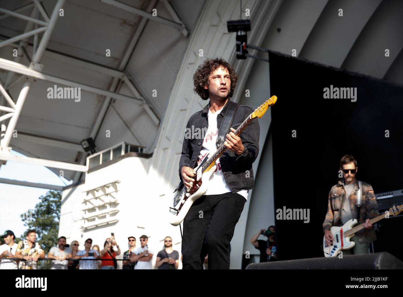Sam Roberts plays guitar and sings on stage wearing a denim jacket and ...