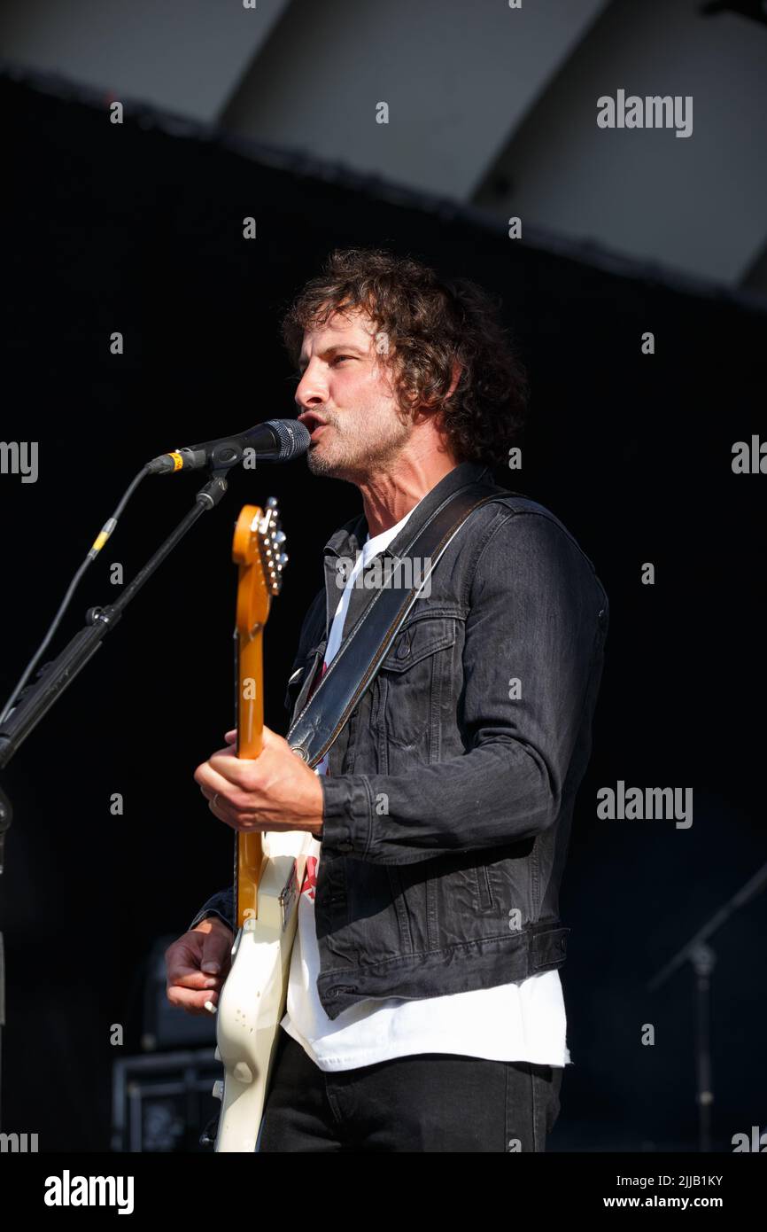 Sam Roberts plays guitar and sings on stage wearing a denim jacket and ...