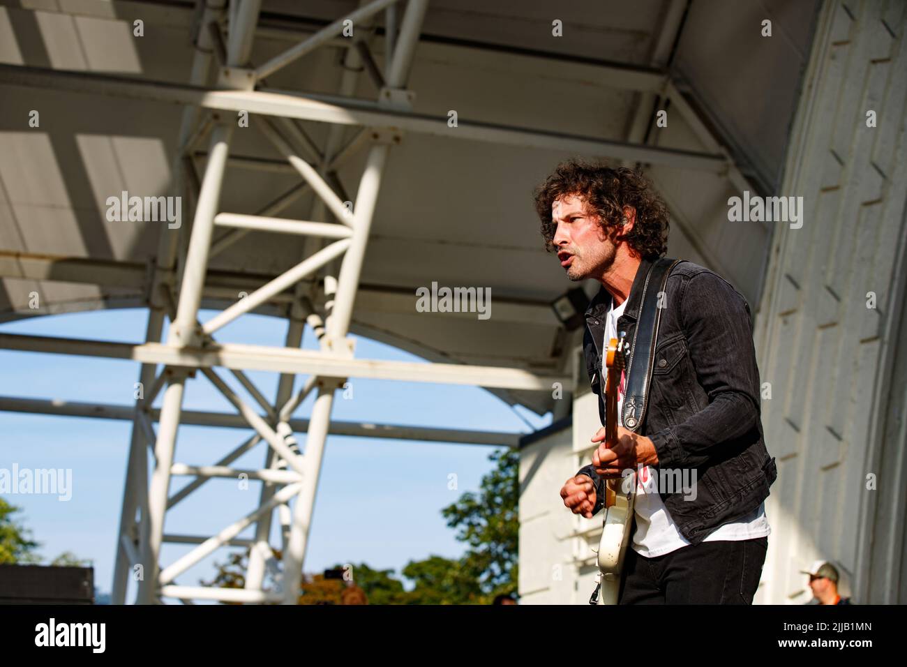 Sam Roberts plays guitar and sings on stage wearing a denim jacket and ...