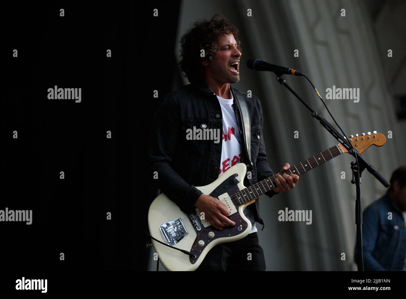 Sam Roberts plays guitar and sings on stage wearing a denim jacket and ...