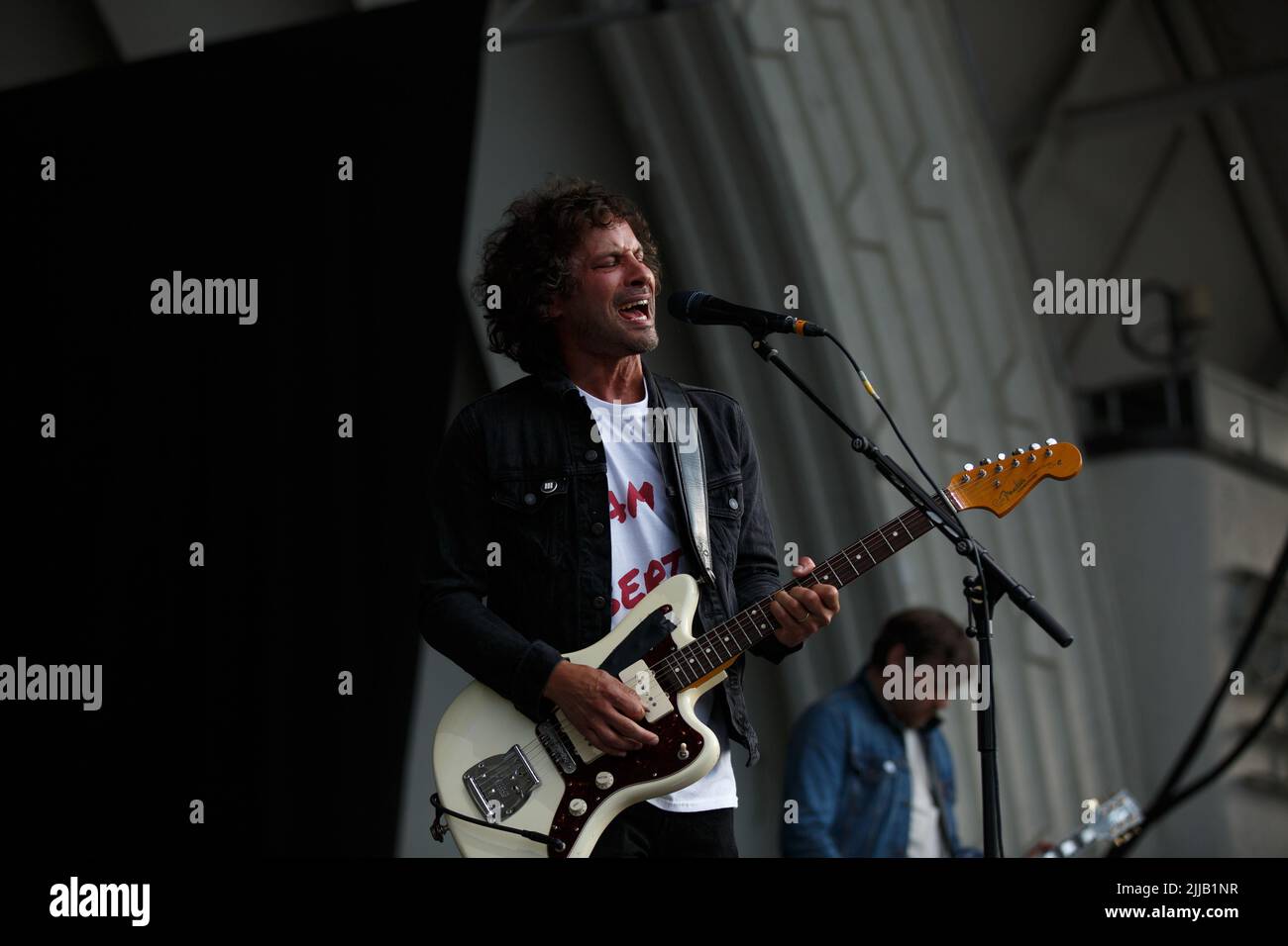 Sam Roberts plays guitar and sings on stage wearing a denim jacket and ...