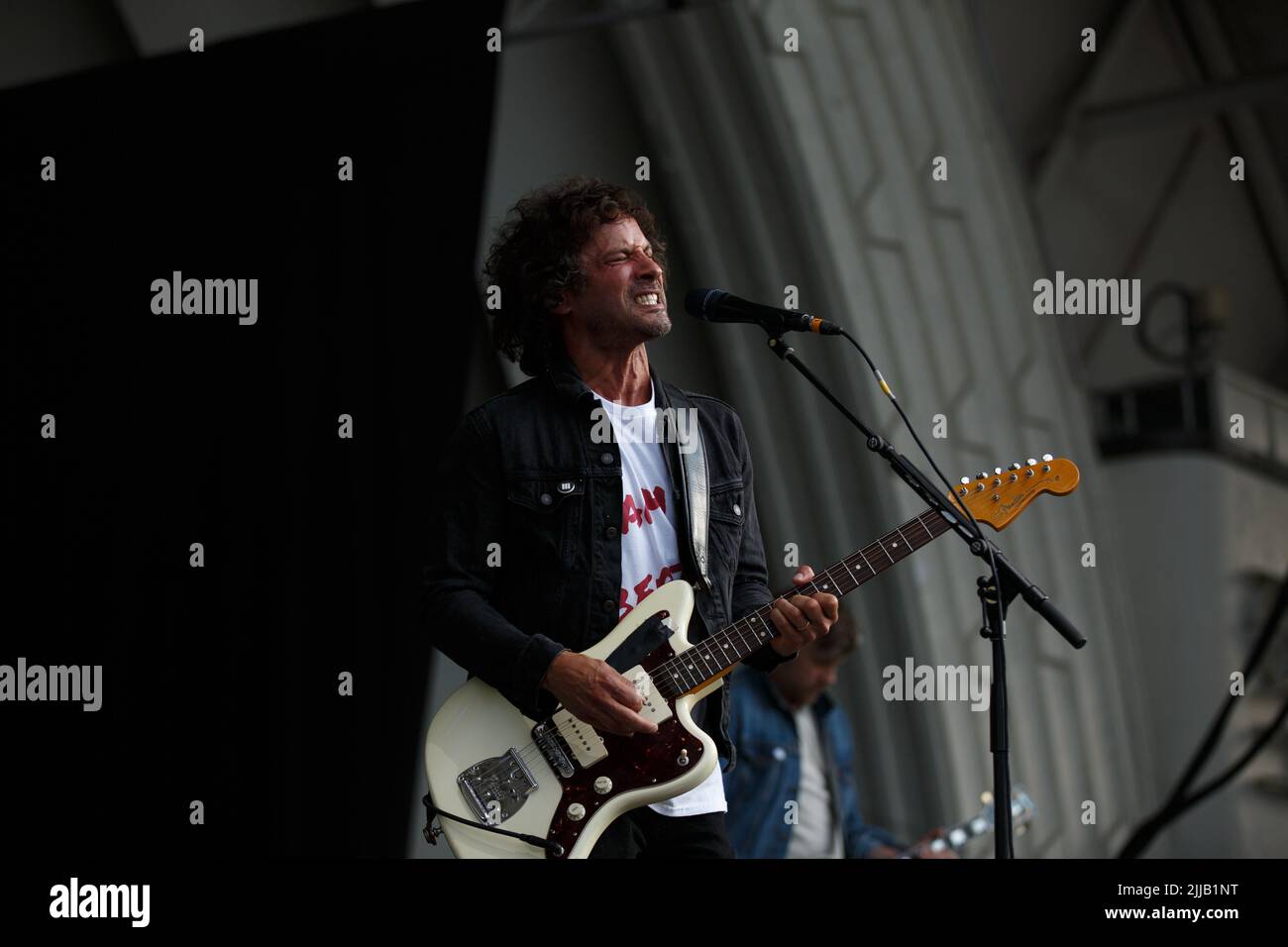 Sam Roberts plays guitar and sings on stage wearing a denim jacket and ...