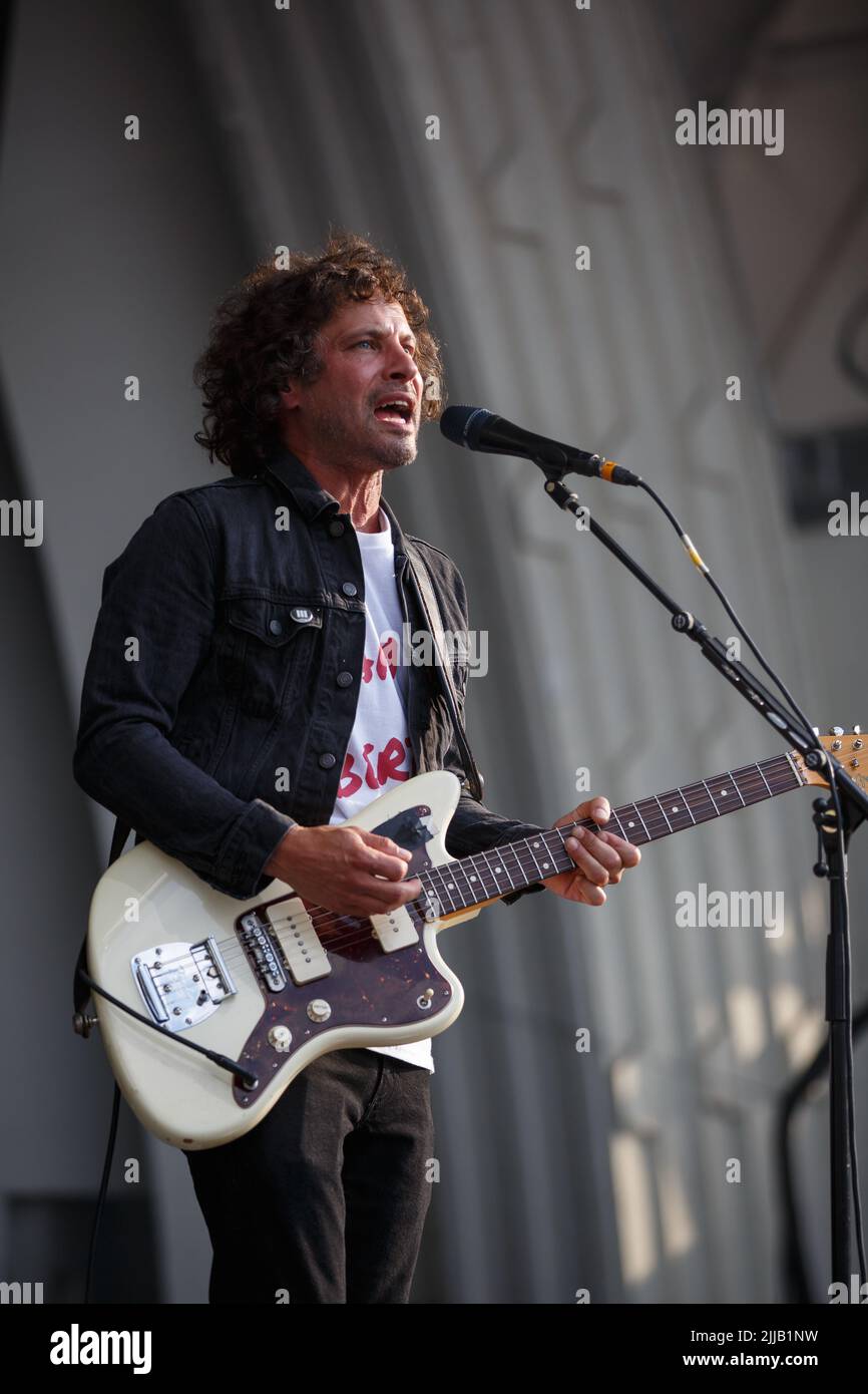 Sam Roberts plays guitar and sings on stage wearing a denim jacket and ...