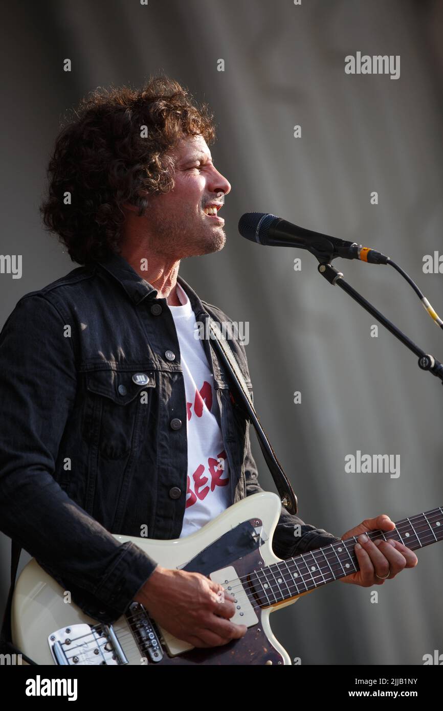 Sam Roberts plays guitar and sings on stage wearing a denim jacket and ...
