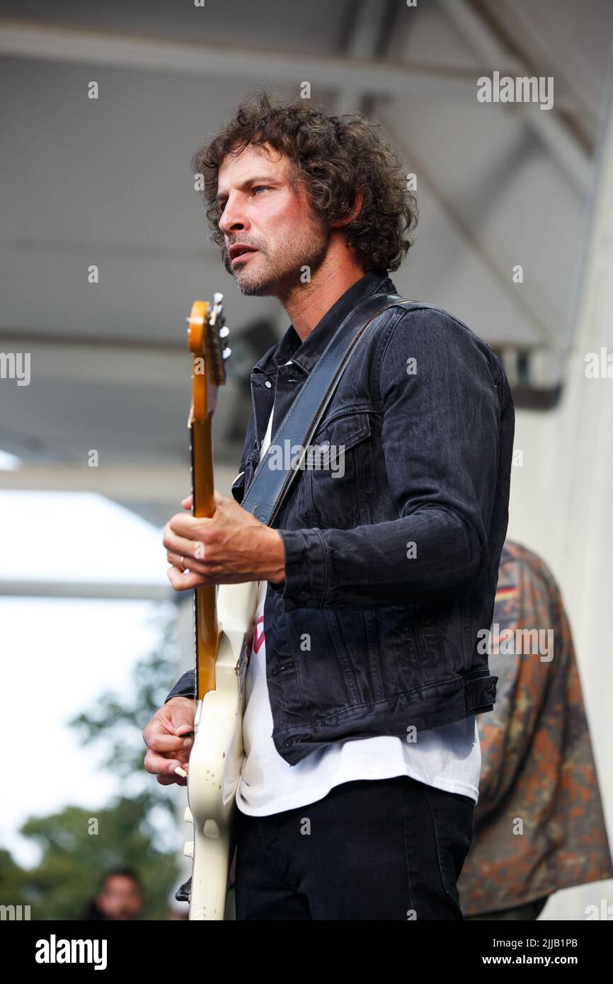 Sam Roberts plays guitar and sings on stage wearing a denim jacket and ...