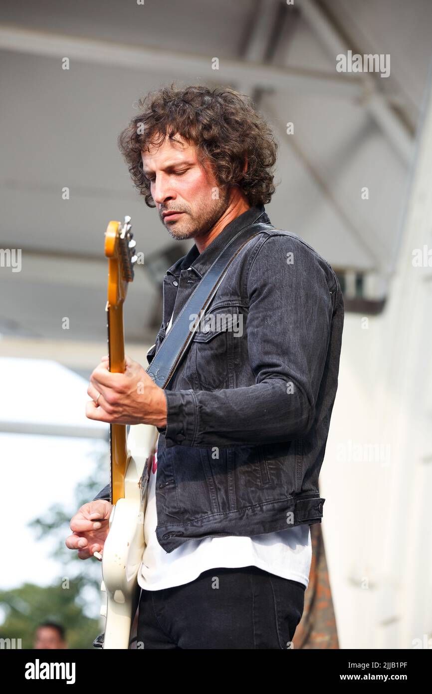 Sam Roberts plays guitar and sings on stage wearing a denim jacket and ...