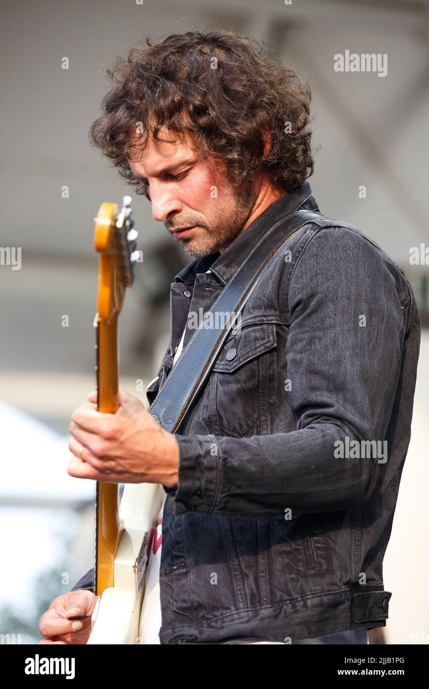 Sam Roberts plays guitar and sings on stage wearing a denim jacket and ...