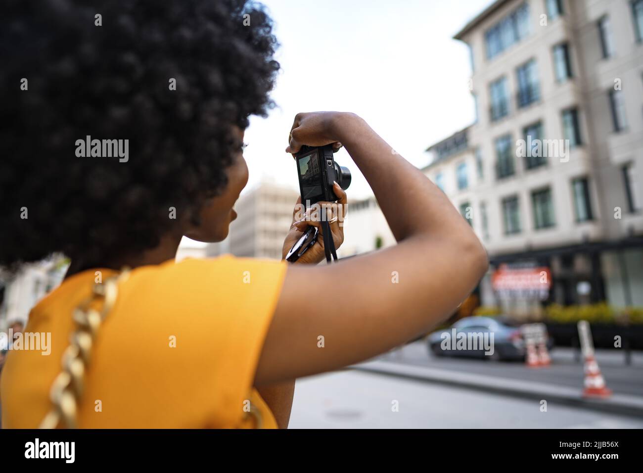 Smiling African american woman using professional camera at a street ...