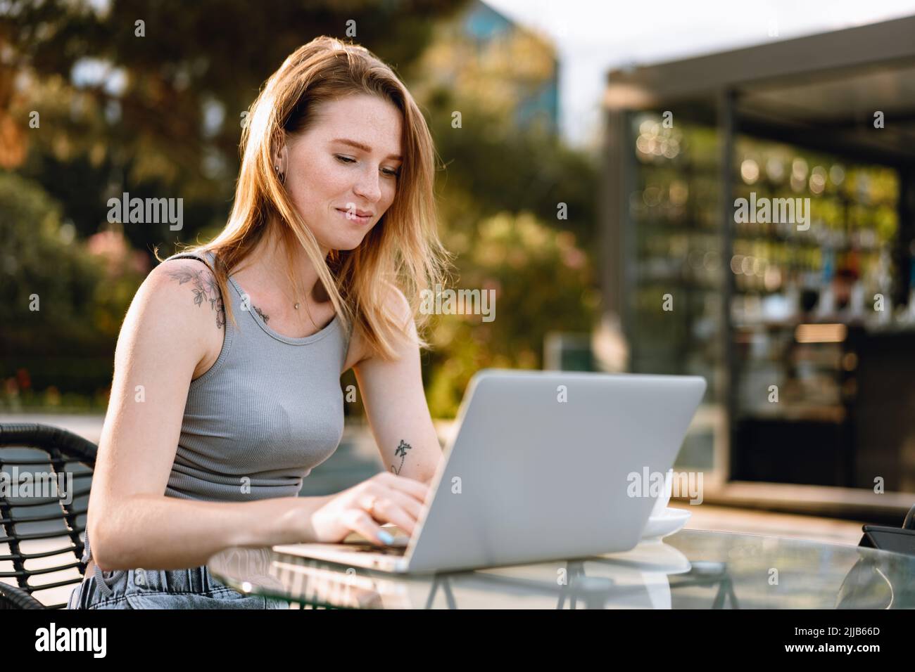 Happy beautiful young woman working on laptop in street cafe Stock ...