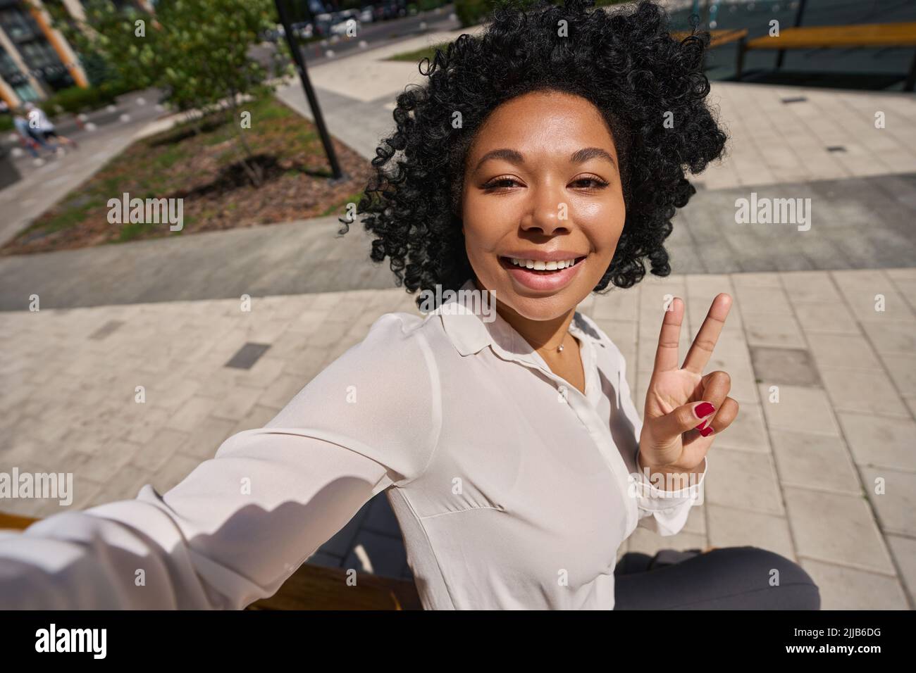 Multiracial female taking selfie showing peace sign Stock Photo - Alamy